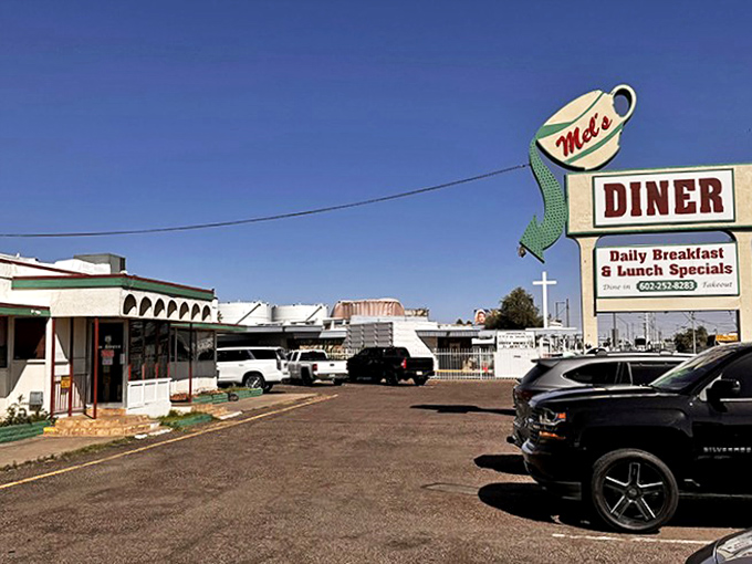 Mel's iconic sign stands tall like a caffeinated sentinel, beckoning hungry travelers with promises of gravy and gossip.