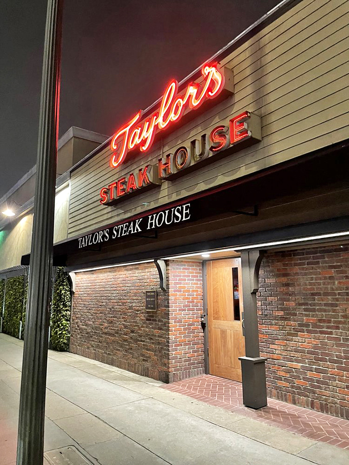 Taylor's red neon glow against brick walls &ndash; a steakhouse beacon that's been calling carnivores home for generations.