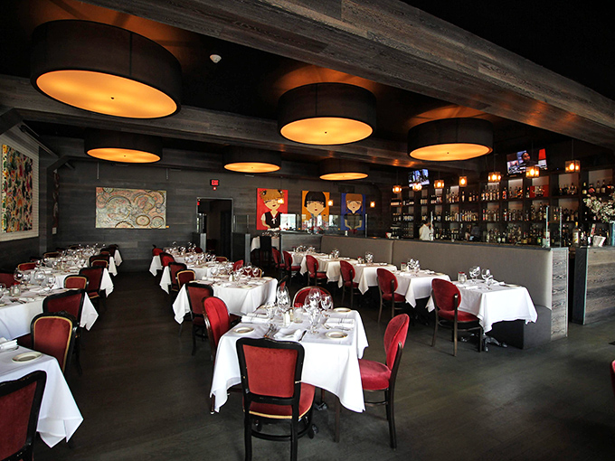 Red chairs, white tablecloths, and amber lighting create the perfect stage for steaks that deserve a standing ovation.