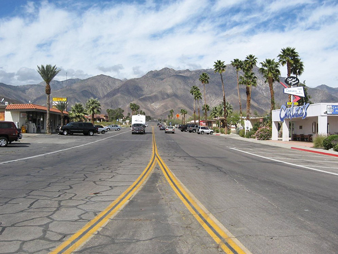 Palm trees stand like exclamation points against mountain backdrops in Borrego Springs' sun-drenched main street.