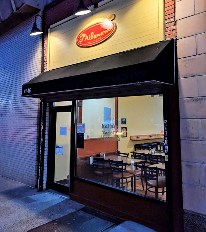 Night transforms Philomena's into a beacon of pizza hope, its glowing interior promising cheesy salvation.