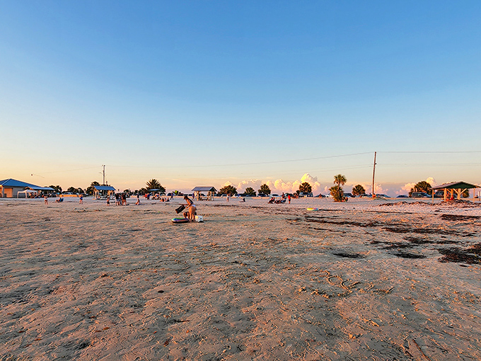 Golden hour transforms Fort Island Beach into a painter's palette of warm hues, with beachgoers becoming silhouettes against the evening sky.
