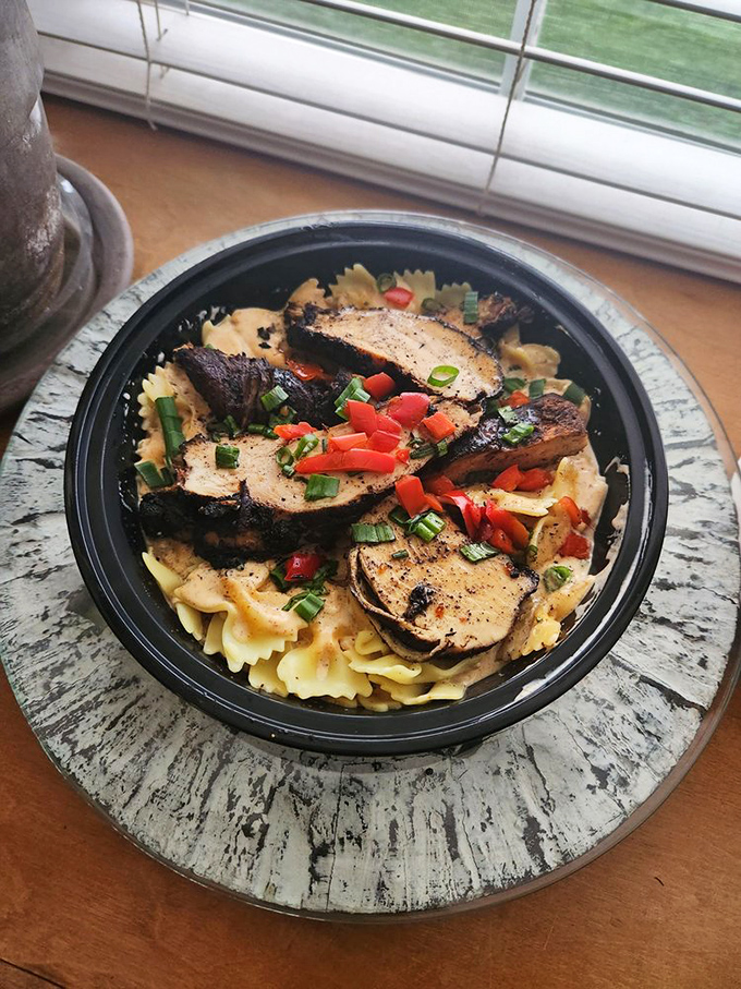Blackened chicken atop bowtie pasta, garnished with fresh peppers and herbs &ndash; proof that paradise can indeed be found in a takeout container.