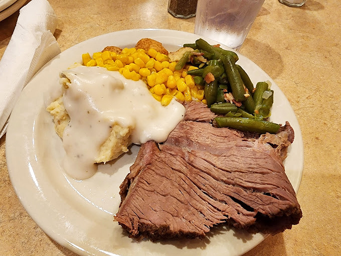 A plate that tells the story of America: perfectly carved roast beef, mashed potatoes with gravy, and vegetables pretending to be more than an afterthought.