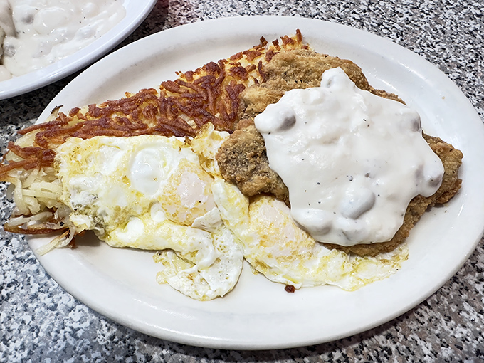 Breakfast nirvana achieved: crispy-edged chicken fried steak meets perfectly runny eggs atop a mountain of hash browns worth climbing.