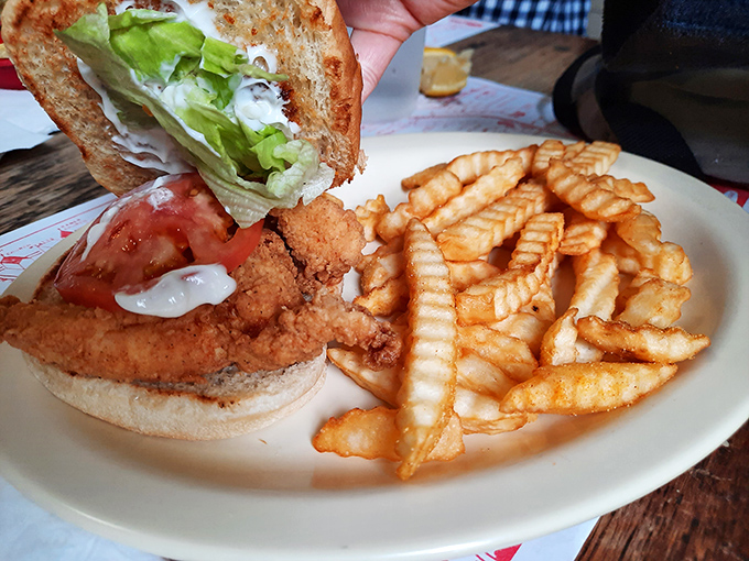 The fried chicken sandwich arrives like Southern comfort on a plate, with those crinkle-cut fries standing at attention, ready for their moment of glory.