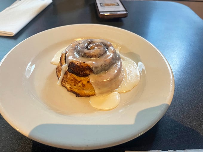 The cinnamon roll arrives like a warm hug on a plate&mdash;glistening, spiraled, and demanding to be the center of attention.