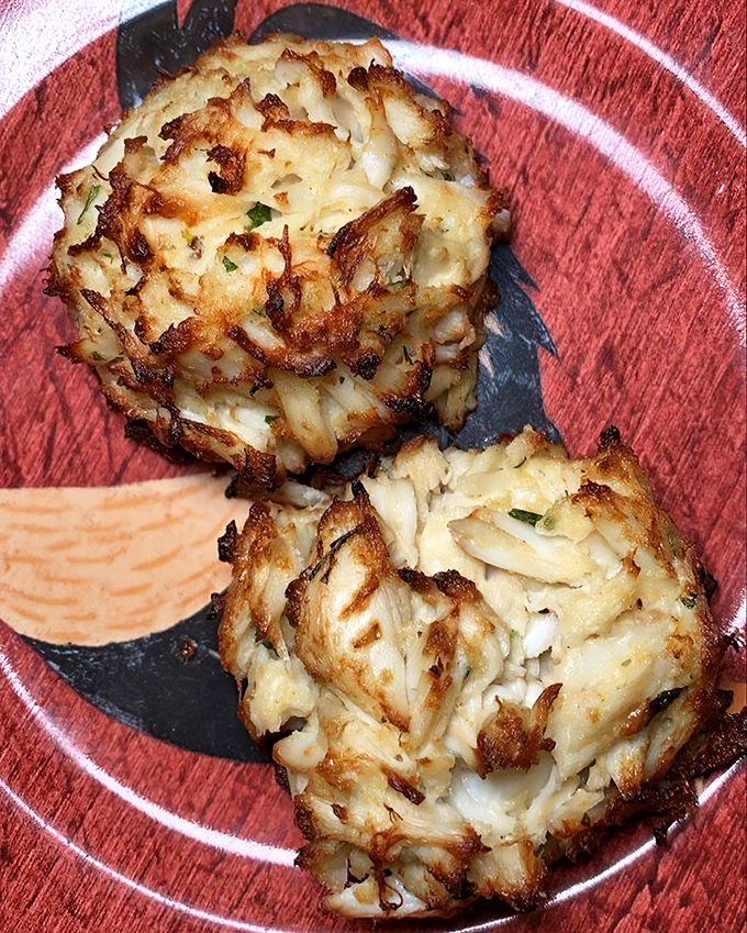 Golden crab cakes packed with sweet meat and minimal filler, accompanied by sauce that complements rather than competes.