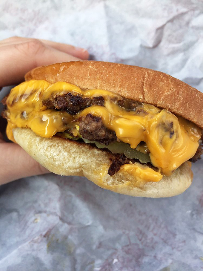 Cheese cascading over perfectly seared patties like a yellow waterfall of happiness. This is burger architecture at its finest.