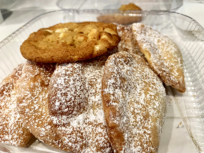 Golden-brown empanadas dusted with powdered sugar alongside a classic cookie&mdash;proof that heaven exists and it's made of pastry.