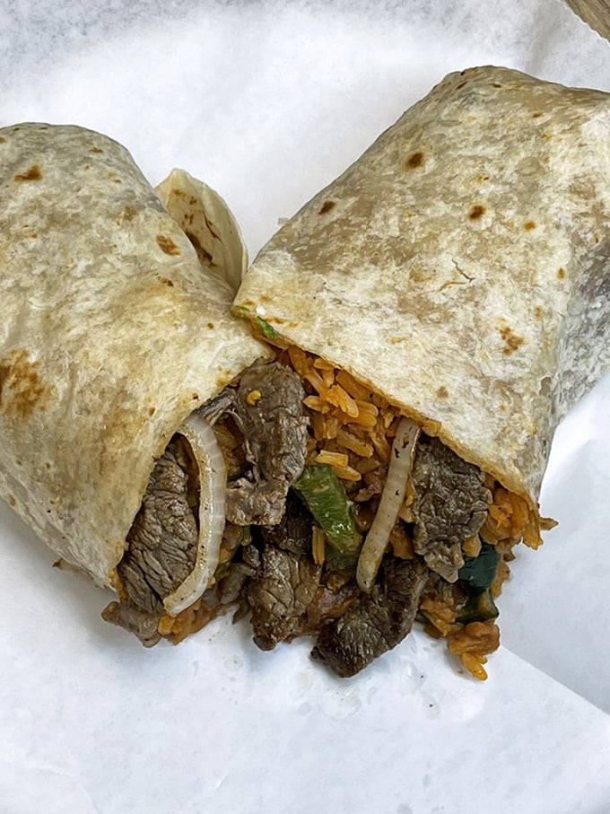 Cross-section perfection: tender steak, seasoned rice, and fresh veggies wrapped in a warm tortilla. It's architectural genius you can eat with your hands.