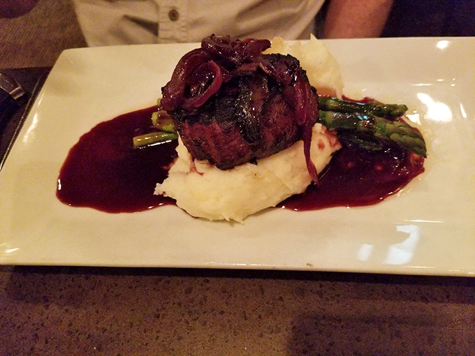 Filet mignon that's dressed better than most wedding guests, perched atop mashed potatoes like royalty on a cloud. The sauce? Pure liquid luxury.
