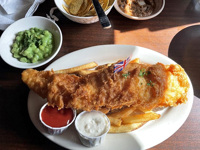 The holy trinity of British comfort: golden fish, proper chips, and vibrant mushy peas. It's like a culinary postcard from London, delivered to your Indiana table.