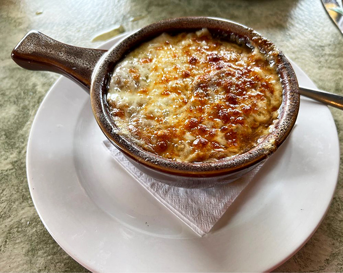 The French onion soup arrives bubbling hot, its golden cheese cap hiding a savory treasure below. Worth every inevitable cheese pull.