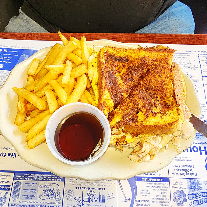 This isn't just French toast &ndash; it's a golden-brown masterpiece flanked by crispy fries and a dipping cup of syrup standing by for duty.