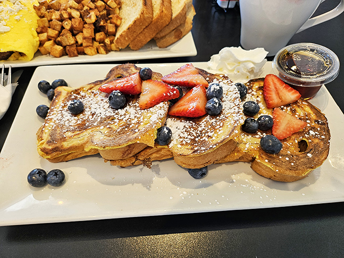 French toast that deserves its own Instagram account&mdash;golden perfection crowned with fresh berries that pop against powdered sugar like edible confetti.