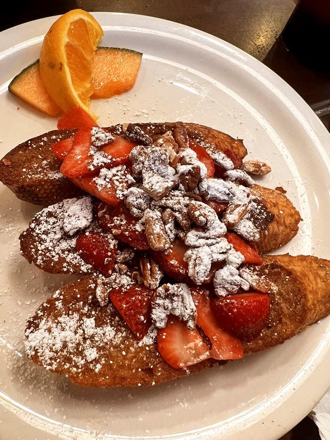 French toast transformed into a celebration, with fresh strawberries, powdered sugar, and candied pecans creating breakfast nirvana.