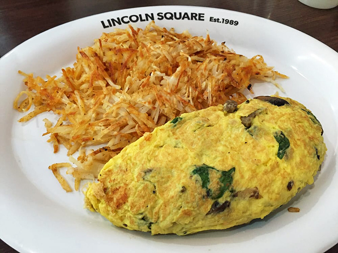 This isn't just an omelet&mdash;it's an architectural achievement. Golden eggs wrapped around veggies with a mountain of hash browns that achieve the impossible: crispy outside, tender inside.