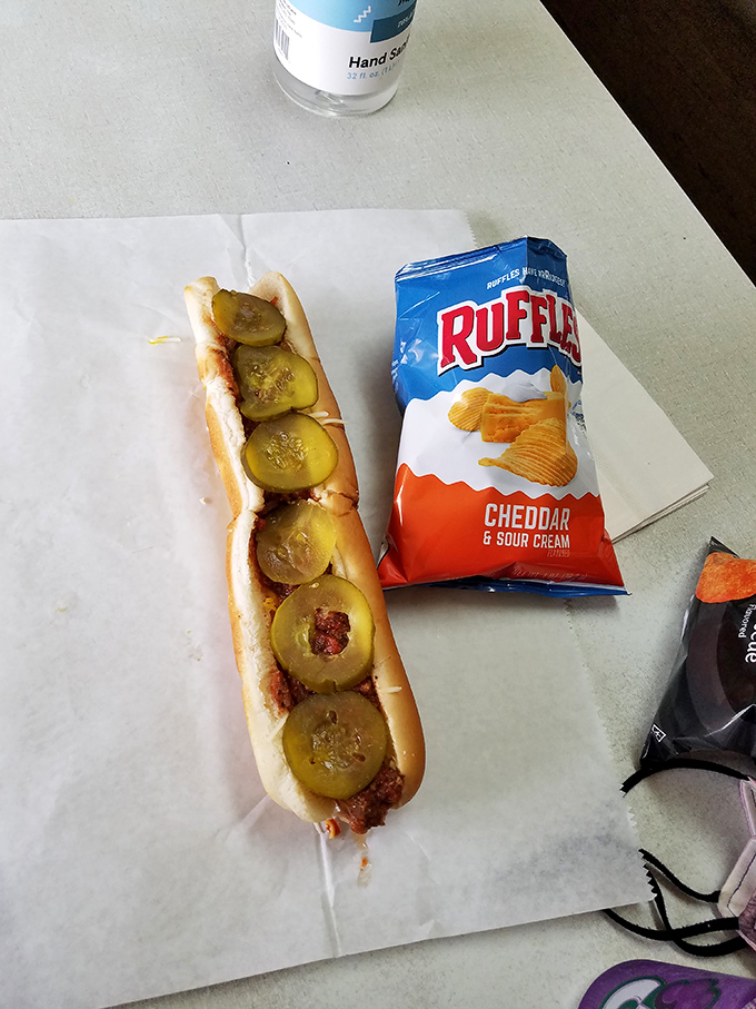 Paired with classic ridged chips, Remo's pickle-topped hot dog proves that some culinary combinations have achieved perfection without needing reinvention.