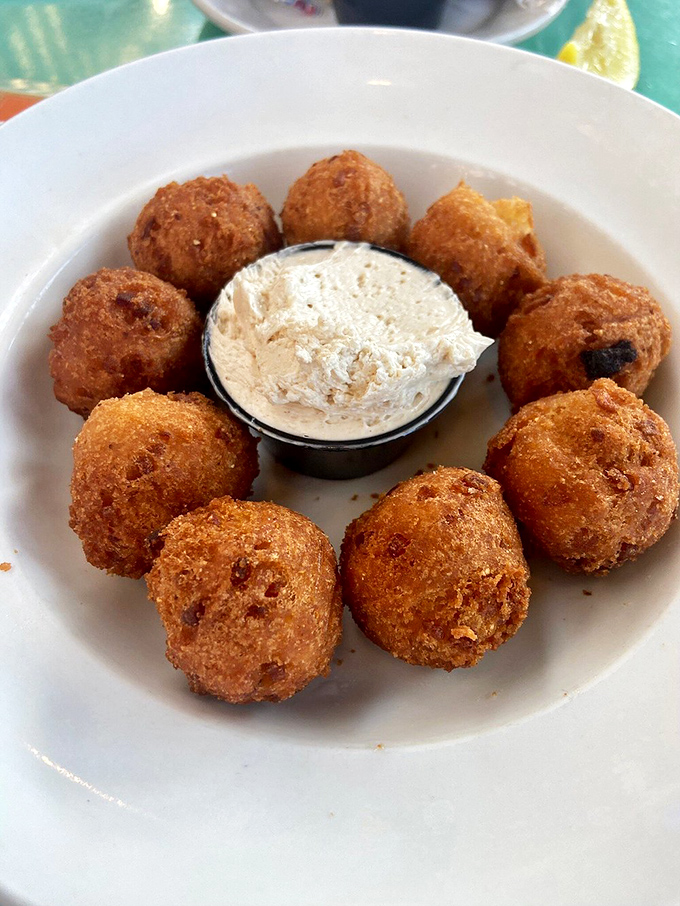 These golden hush puppies form a perfect circle of Southern comfort, standing guard around a creamy dip that demands to be explored. 