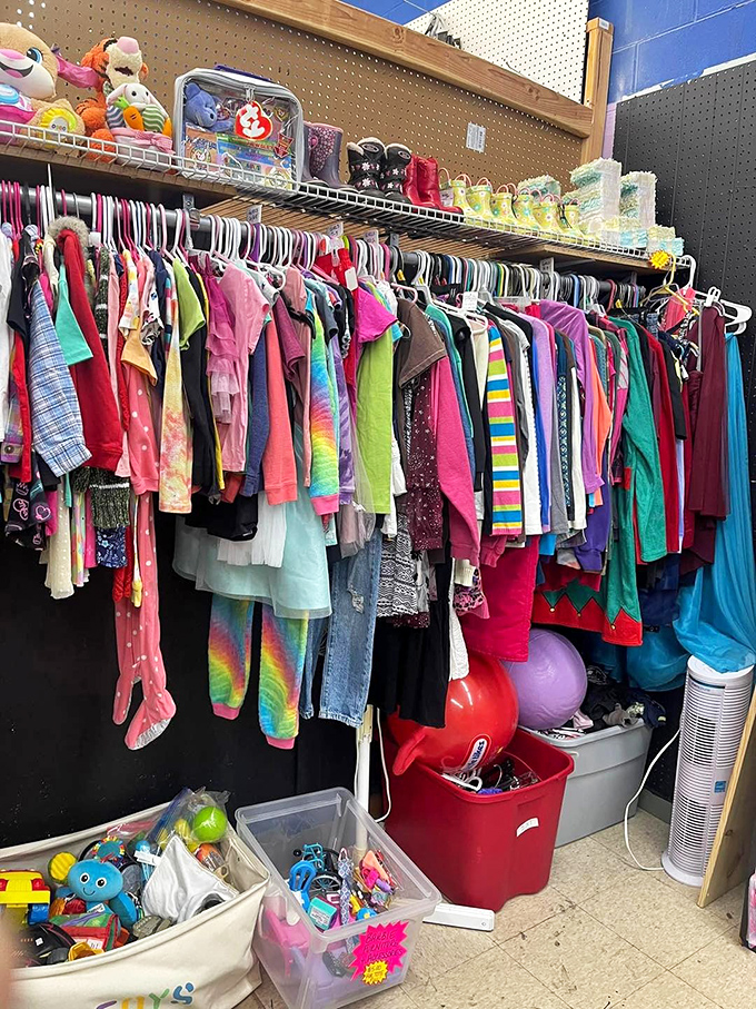 A rainbow explosion of children's clothing hangs alongside toys and stuffed animals, proving that even outgrown treasures deserve second chances.