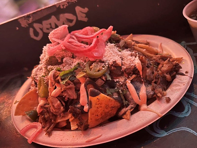 A mountain of nachos that requires a climbing permit and a serious appetite. The pickled onions cut through richness like a magenta-colored flavor ninja.
