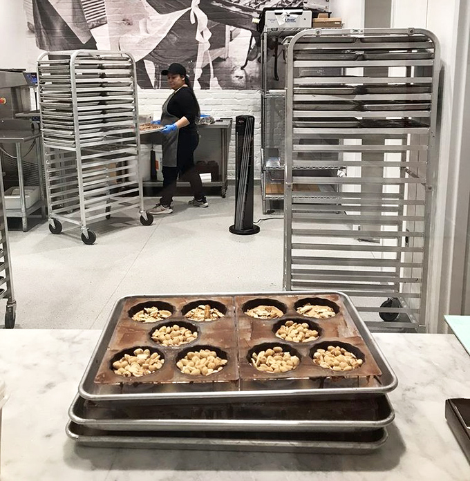 Behind the scenes, artisans prepare handcrafted treats with meticulous care, arranging peanuts in chocolate cups like jewelers setting precious stones.