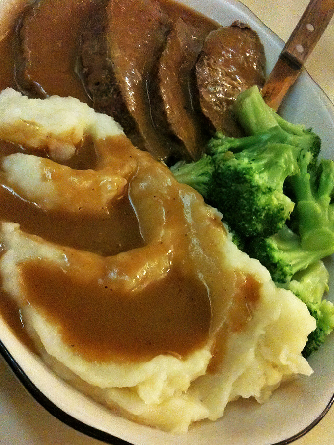 The holy trinity of diner perfection: meatloaf, mashed potatoes, and bright green broccoli. A balanced meal that satisfies both mom and your taste buds.