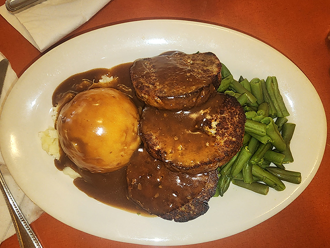 The holy trinity of comfort: perfectly seasoned meatloaf, cloud-like mashed potatoes, and green beans that actually taste like vegetables should.