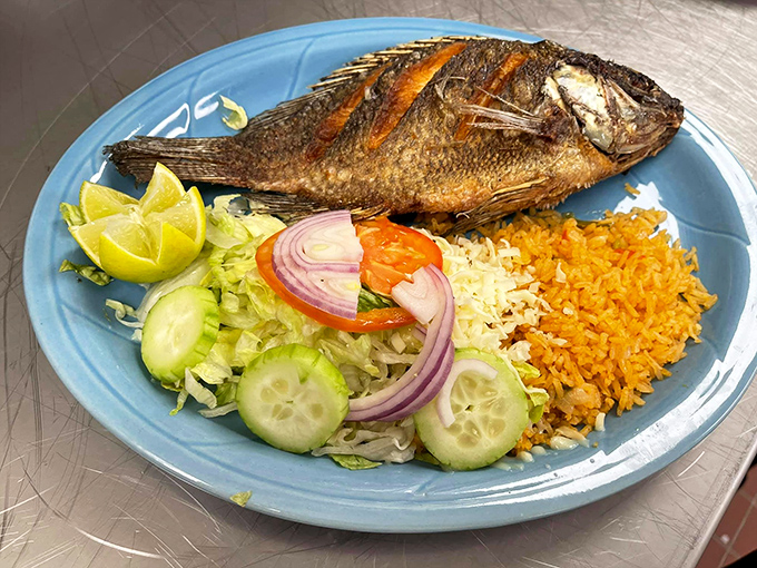 The whole fish arrives like it's making a grand entrance, surrounded by a supporting cast of fresh vegetables and that signature golden rice.