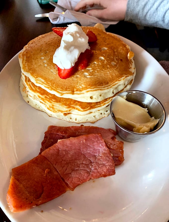 Pancake perfection topped with fresh strawberries and a side of country ham. Breakfast harmony achieved on a single plate.