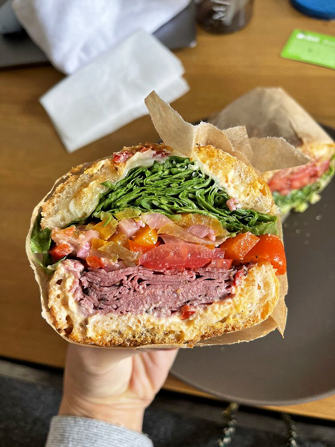 Cross-section perfection reveals the architectural genius behind each sandwich. This pastrami creation showcases the art of proper ingredient layering.