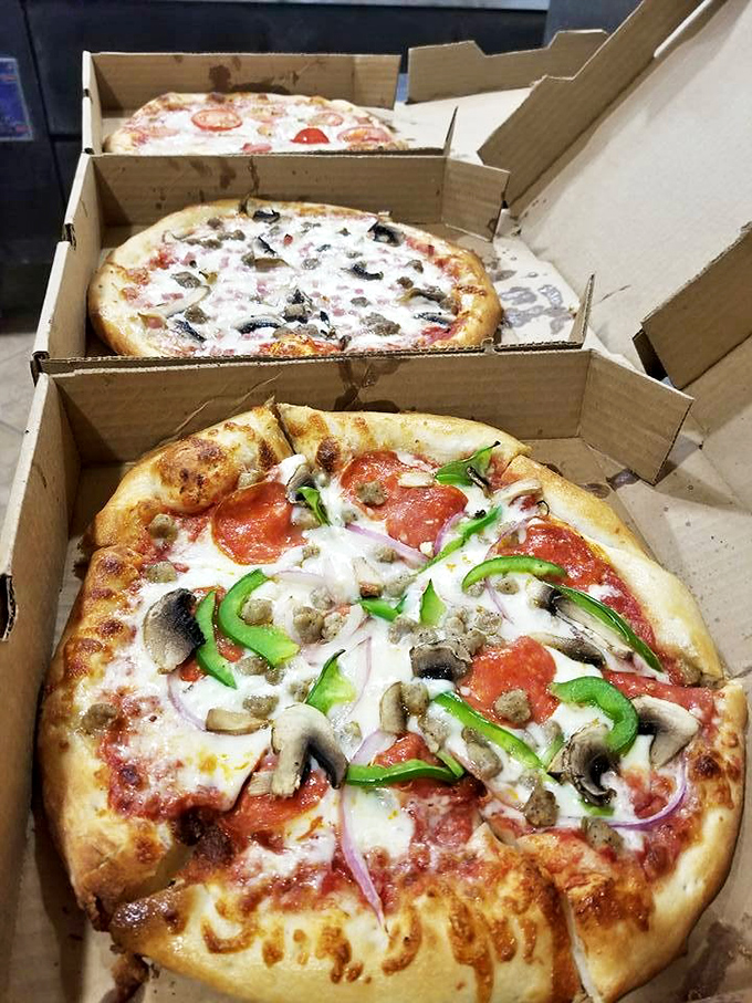 Pizza boxes stacked like Russian nesting dolls of flavor, each one promising a different journey for your taste buds.