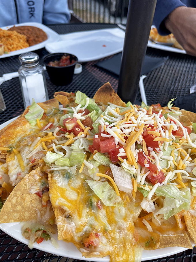 Layer upon glorious layer of cheese, lettuce, and tomato. This plate of nachos doesn't just satisfy hunger—it negotiates peace with it.
