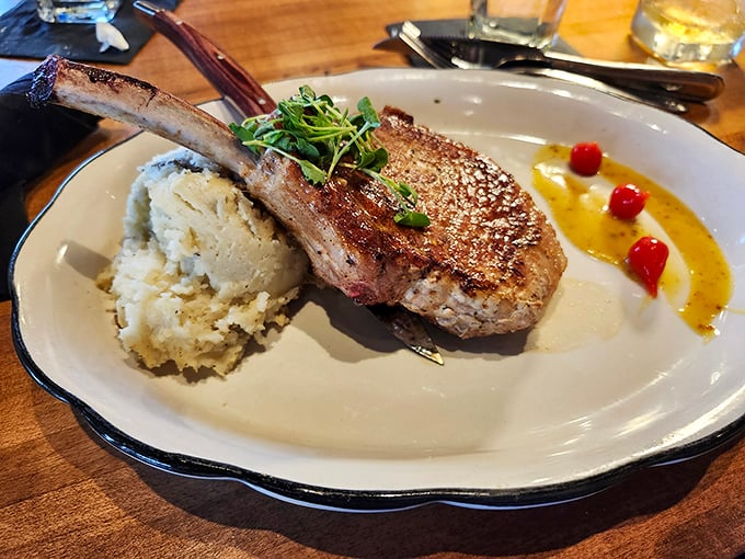 This pork chop isn't just dinner &ndash; it's architecture with a bone handle, served alongside mashed potatoes that could make a Frenchman weep.
