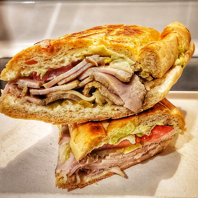 Cross-section perfection reveals the architectural wonder that is a proper Cuban sandwich. Each layer visible, like delicious geological strata.