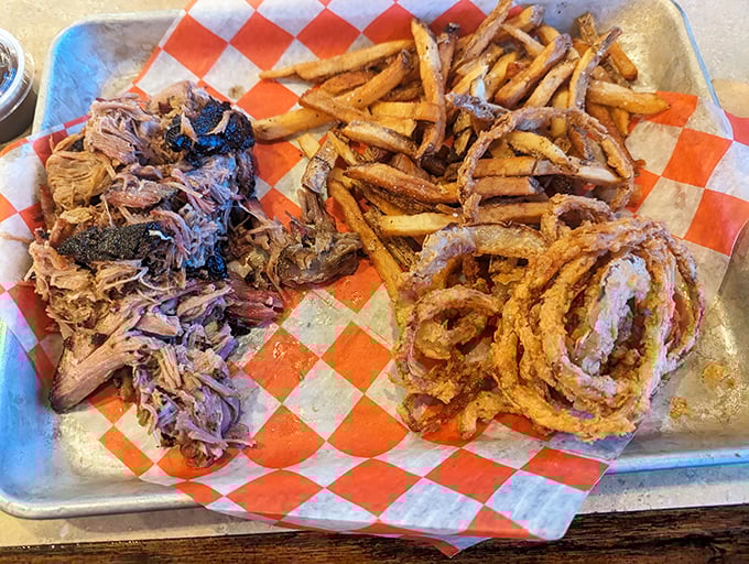 Barbecue perfection on a metal tray: hand-pulled pork alongside crispy fries and those onion rings that make you forget counting calories was ever a thing.