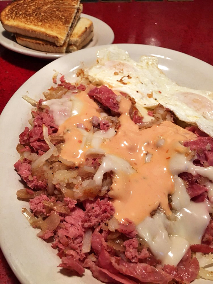 Breakfast alchemy at its finest: corned beef hash topped with eggs and that mysterious orange sauce that makes everything better.
