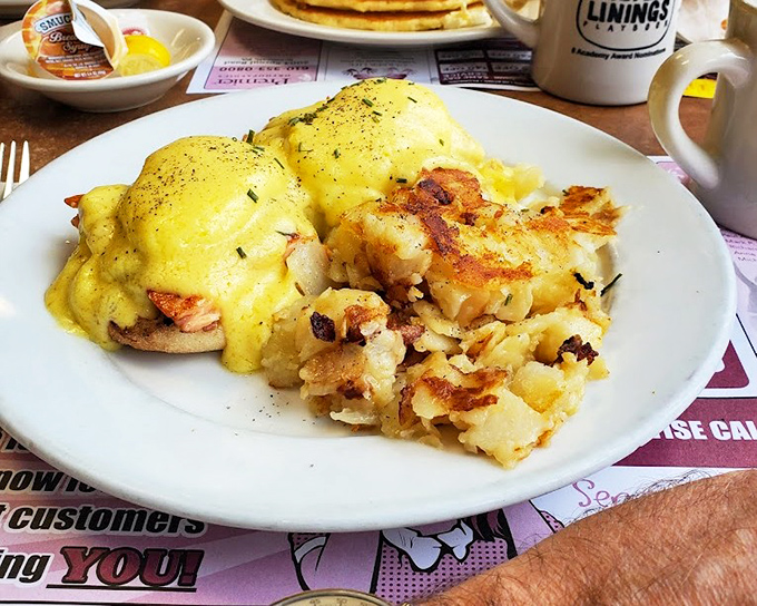 Eggs Benedict reimagined&mdash;golden hollandaise cascading over perfectly poached eggs like a breakfast waterfall, with home fries that demand equal attention. 