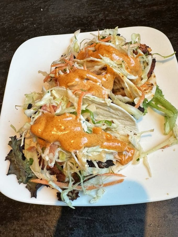 These salmon tacos don't just speak to you; they sing a siren song of fresh seafood, crunchy slaw, and that sauce that'll haunt your dreams for weeks.