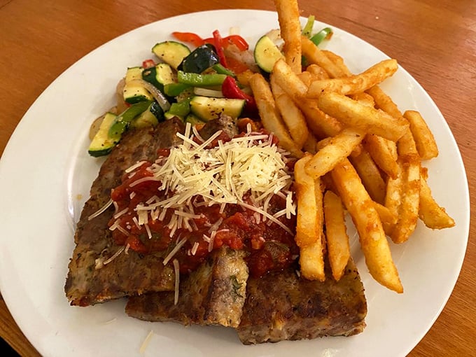 The holy trinity of comfort: perfectly seasoned meatloaf, golden fries, and vegetables that didn't come from a freezer. Grandma would approve, then steal your plate.