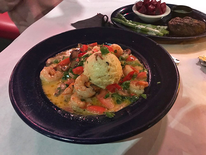 Shrimp and grits elevated to an art form&mdash;plump shellfish swimming in savory broth around a golden cornmeal island. Southern comfort with coastal sophistication.