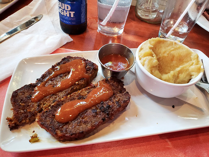 The meatloaf arrives like a rockstar on a white plate, its sauce drizzled with the confidence of something that knows it's irresistible.