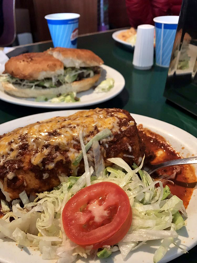 The legendary Smothered Burrito arrives like a celebrity, draped in red sauce and melted cheese, with fresh vegetables providing a paparazzi-worthy garnish.