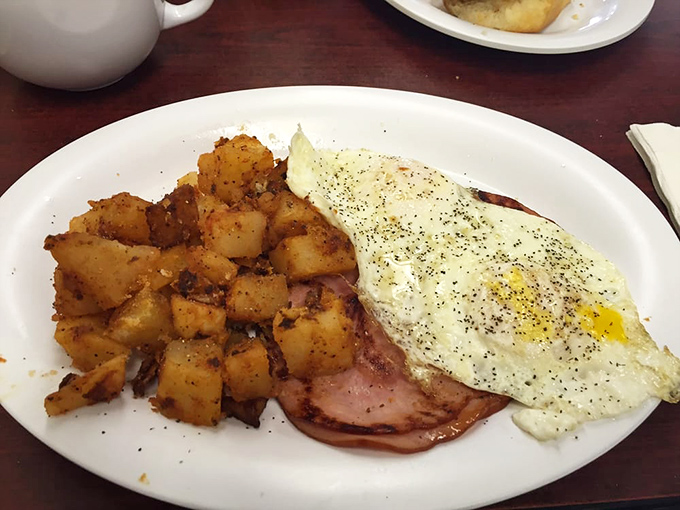 The holy trinity of breakfast: perfectly seasoned home fries, ham sliced just right, and eggs with that ideal runny yolk. Simple perfection on a plate.