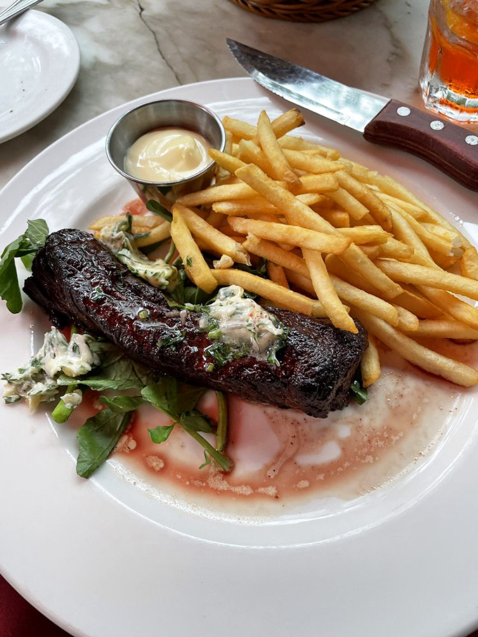 Steak frites done right: a perfectly seared cut, herb butter melting into meat, and fries so crisp they should win awards.
