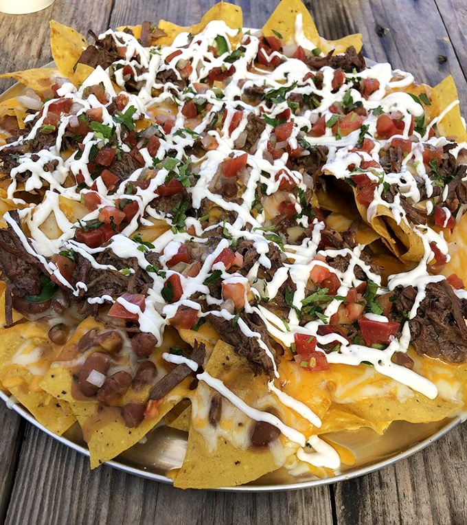 Nacho architecture at its finest! Layers of melted cheese, seasoned meat, fresh pico, and that perfect zigzag of crema create a mountain worth climbing.
