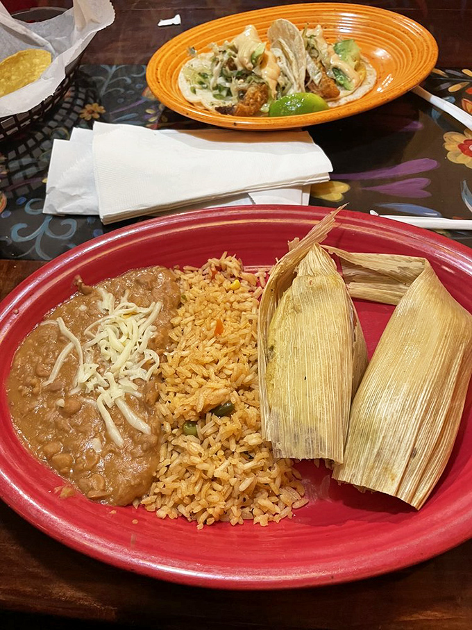 When comfort food crosses borders: tender tamales nestled beside perfectly seasoned rice and beans&mdash;a plate that feels like someone's grandmother is in the kitchen.