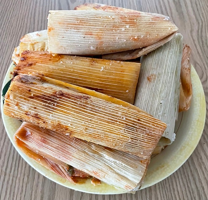 Tamales in their natural habitat&mdash;corn husks cradling treasures within. Like little presents waiting to be unwrapped, each one a perfect package of comfort.