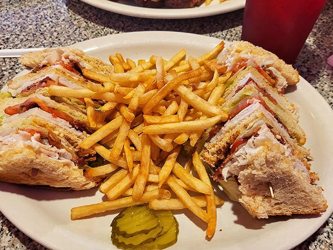 The turkey club sandwich arrives as a towering testament to the art of proper deli construction and crispy fries.
